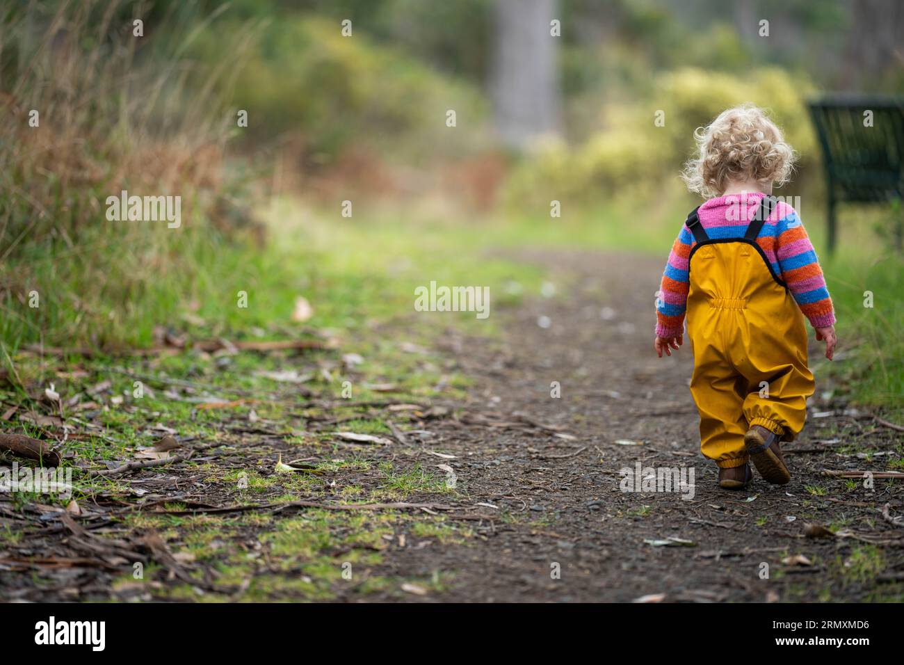 baby running down a path in yellow overalls in the bush Stock Photo - Alamy
