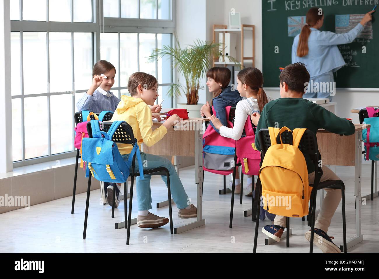 Little pupils with backpacks having lesson in classroom Stock Photo - Alamy