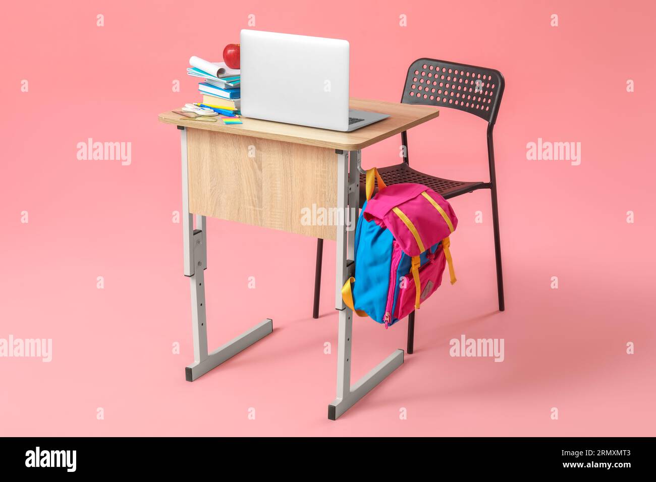 Modern school desk with backpack, laptop and stationery on pink ...