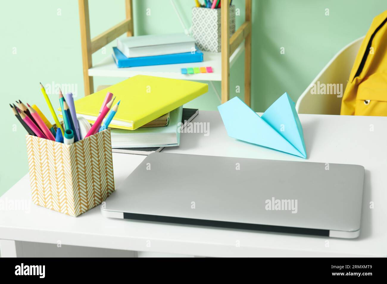 Modern school desk with backpack, laptop and stationery in room near ...