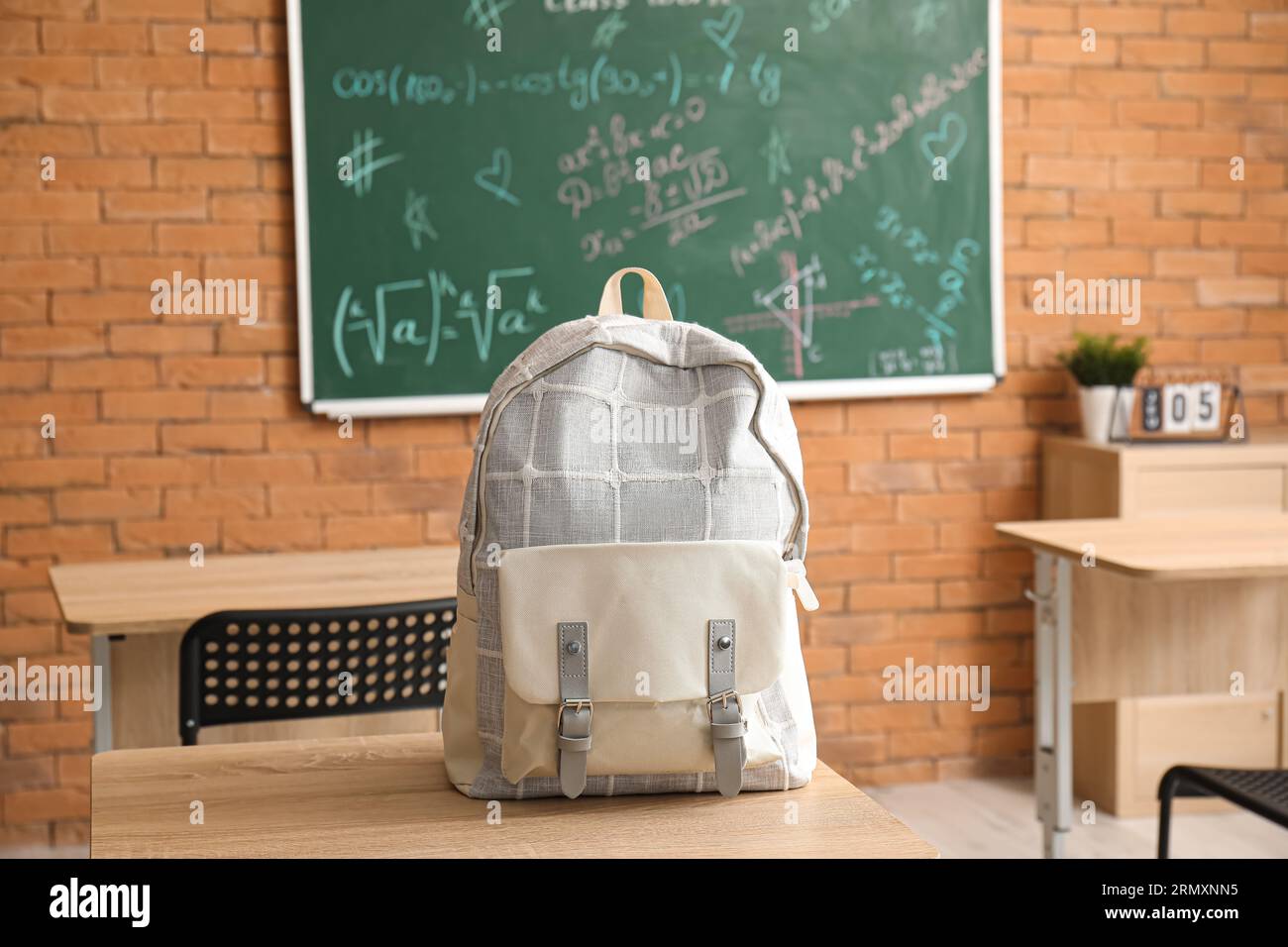 Stylish school backpack on desk in classroom Stock Photo - Alamy