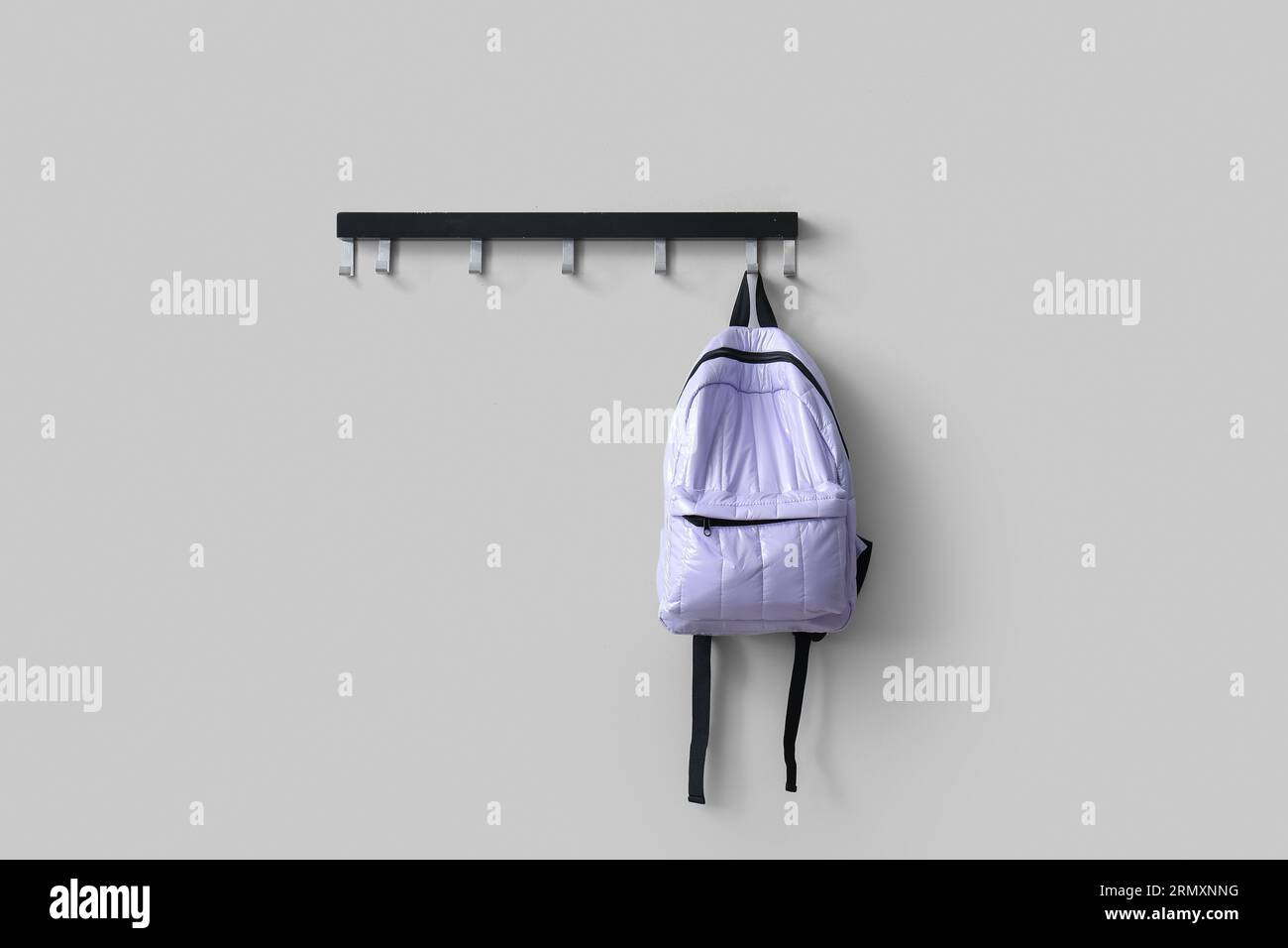 Stylish school backpack hanging on white wall in room Stock Photo - Alamy
