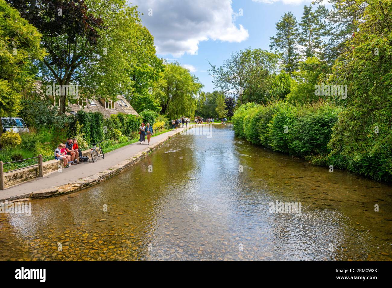 Pedestrians walk along the River Windrush at picturesque Bourton-on-the ...