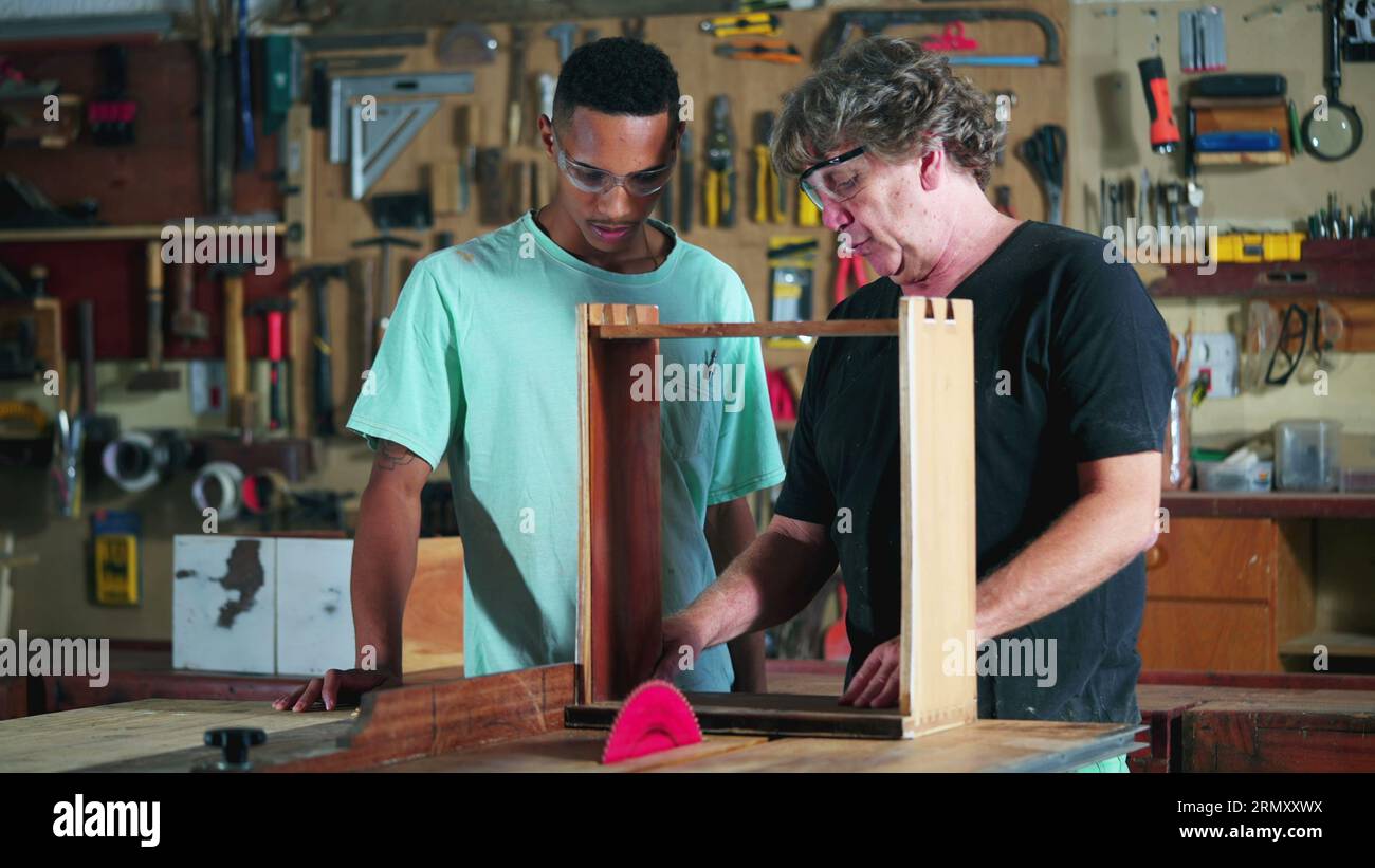Master carpenter guiding apprentice at carpentry workshop, boss ...