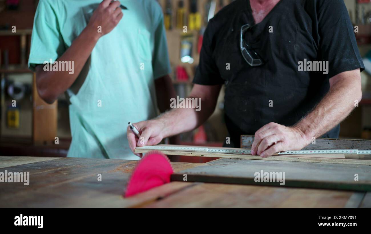 Carpenters measuring length of wood with pen and ruler at carpentry ...