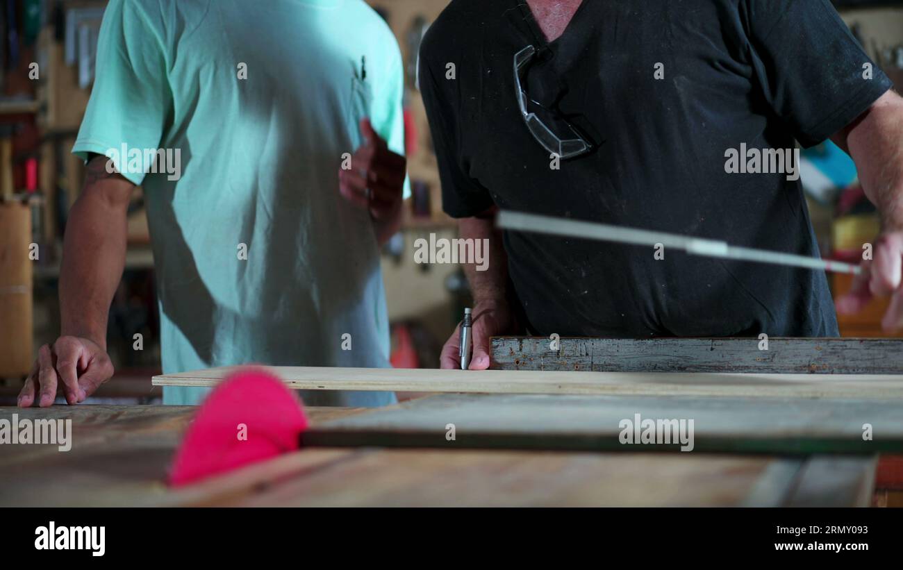 Carpenters measuring length of wood with pen and ruler at carpentry ...