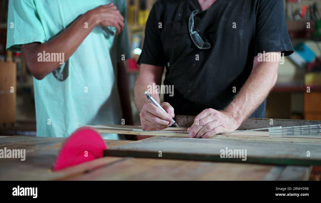 Carpenters measuring length of wood with pen and ruler at carpentry ...