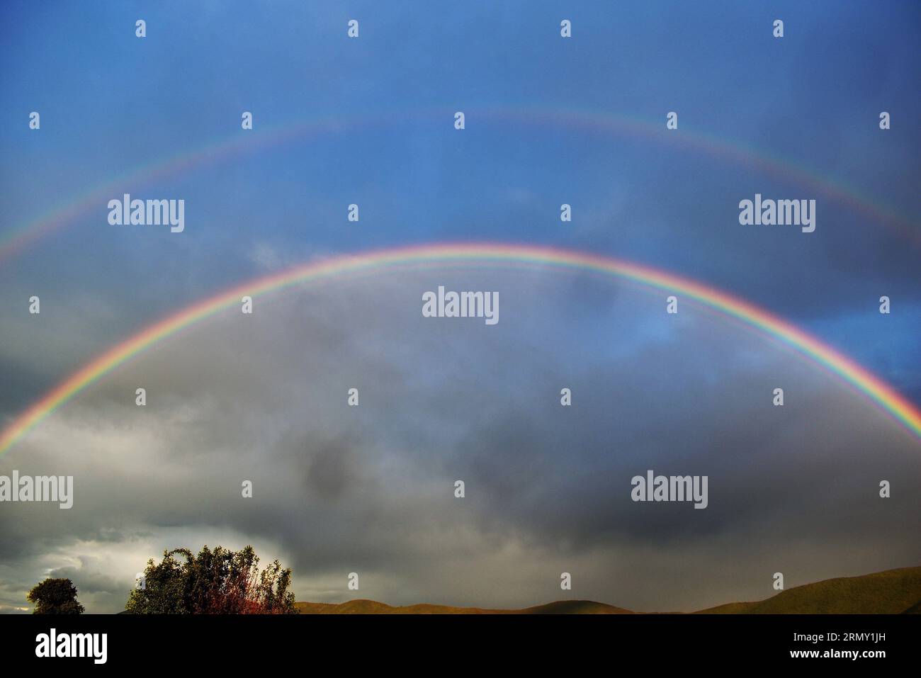 A stunning landscape featuring two double rainbows in the sky over an ...