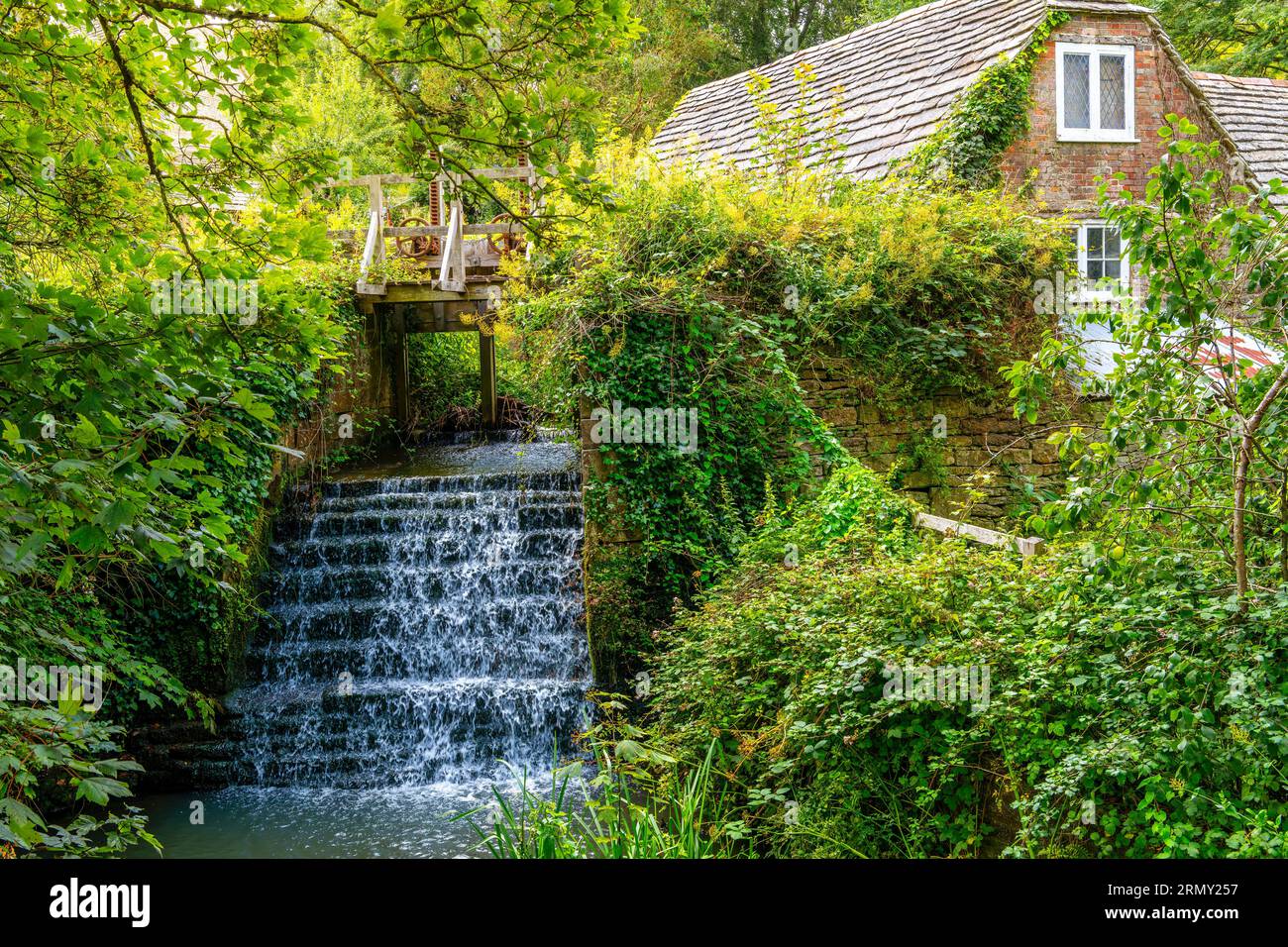 A picturesque stone cottage alongside a water mill and waterfall in the ...