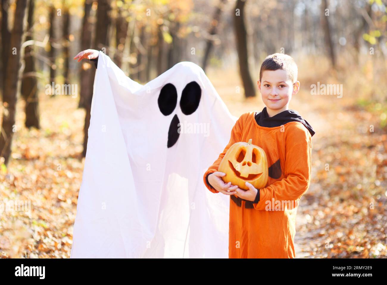 child boy in an orange suit holds a Jack pumpkin in his hands and ...