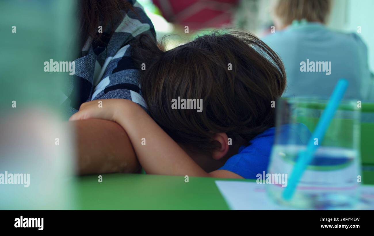 Bored small boy leaning on mother arm feeling boredom at restaurant ...