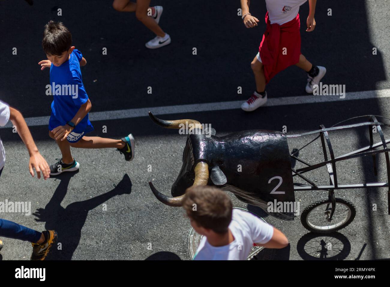 Children run in front of bullfighting carts, during a children's ...