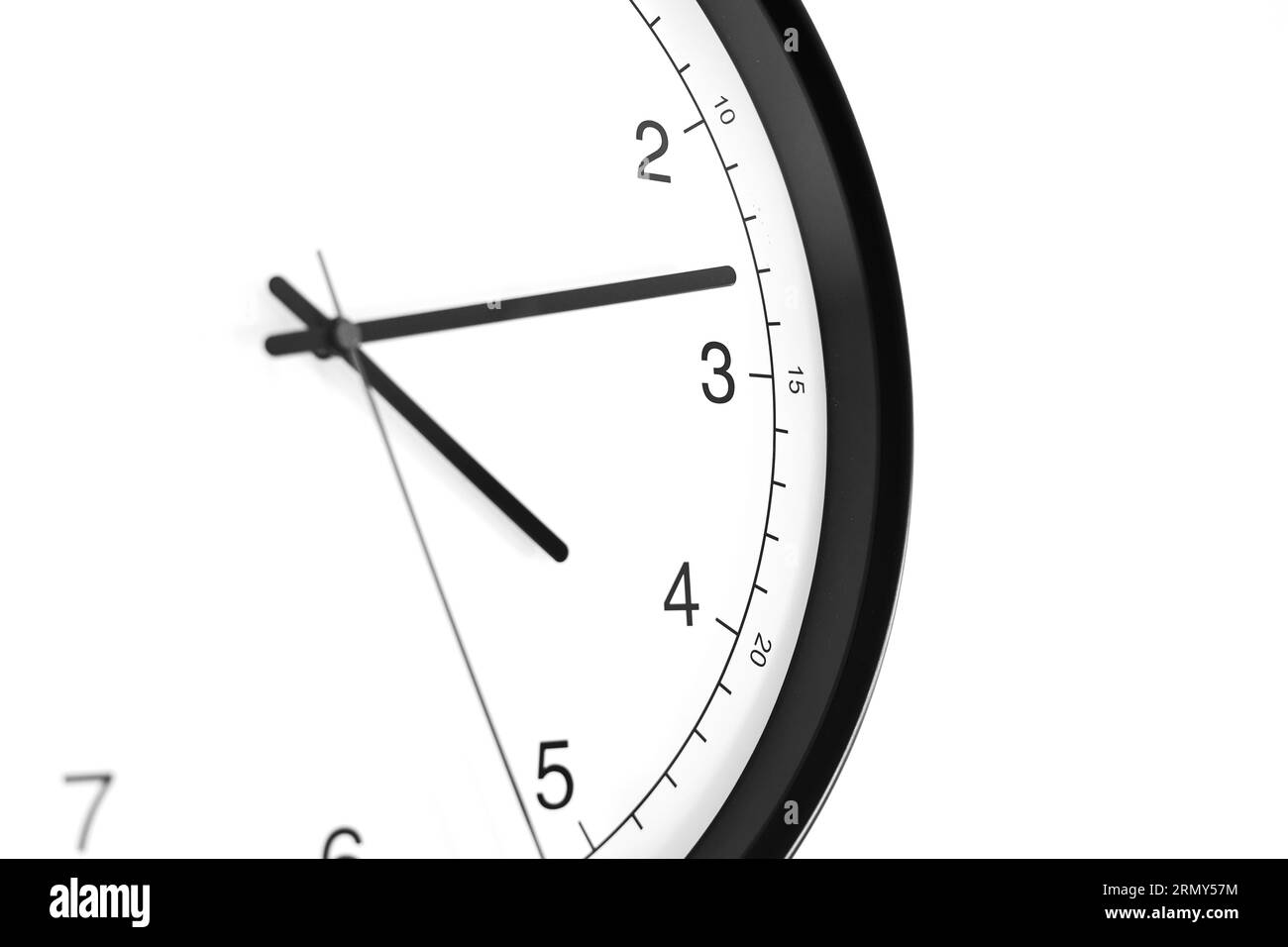 Part of analogue plain wall clock on white wall background. Four o ...