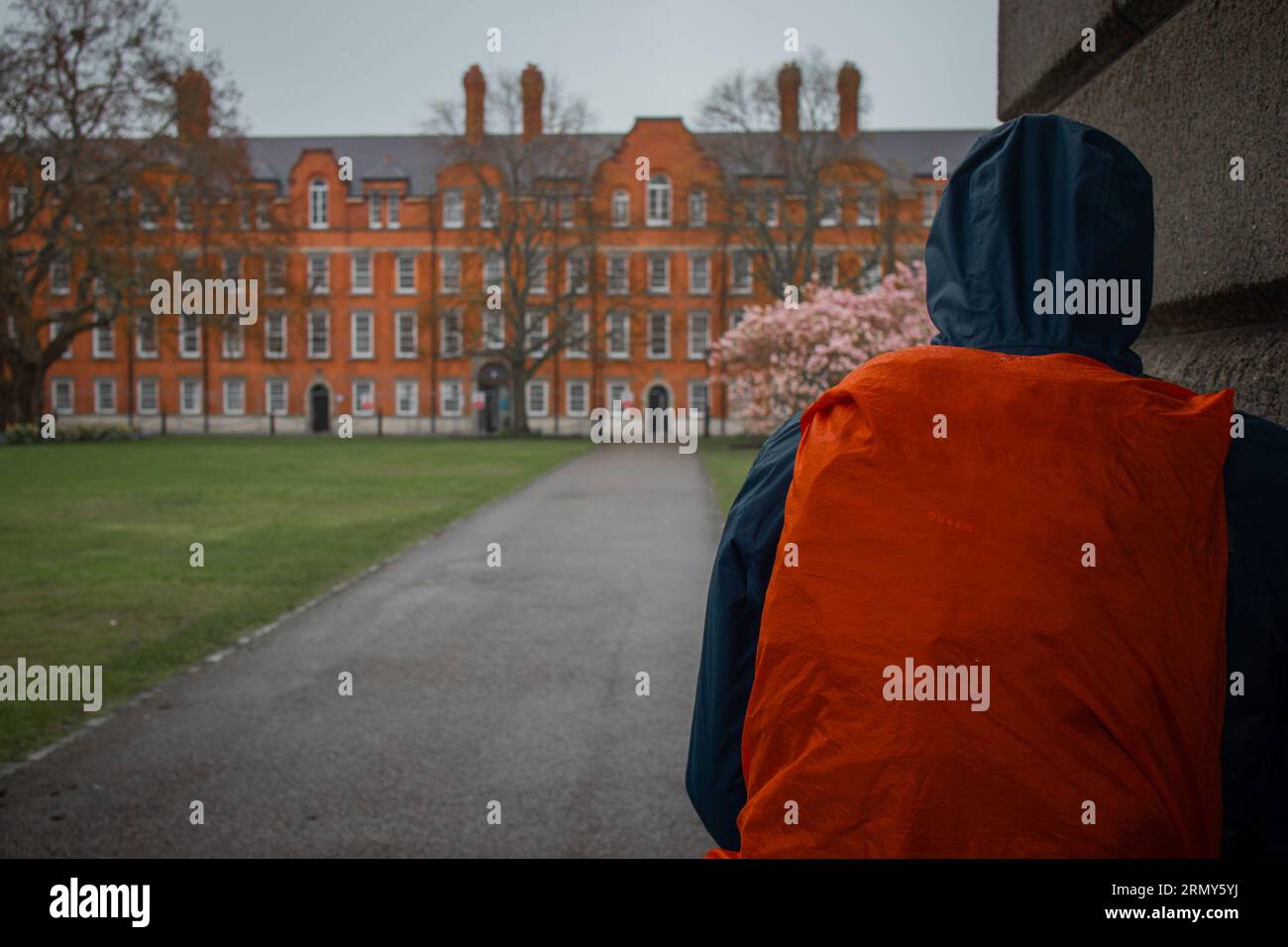 Unknown person in rain jacket and backpack with water protection hiding ...