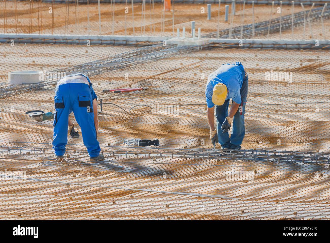 Overview of two construction workers using pincers and fixing steel ...
