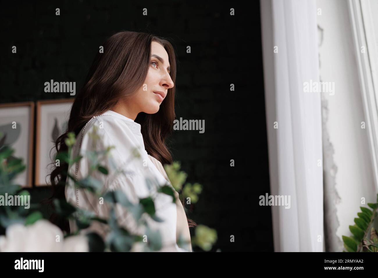 Thoughtful attractive young woman looking outside away through the ...