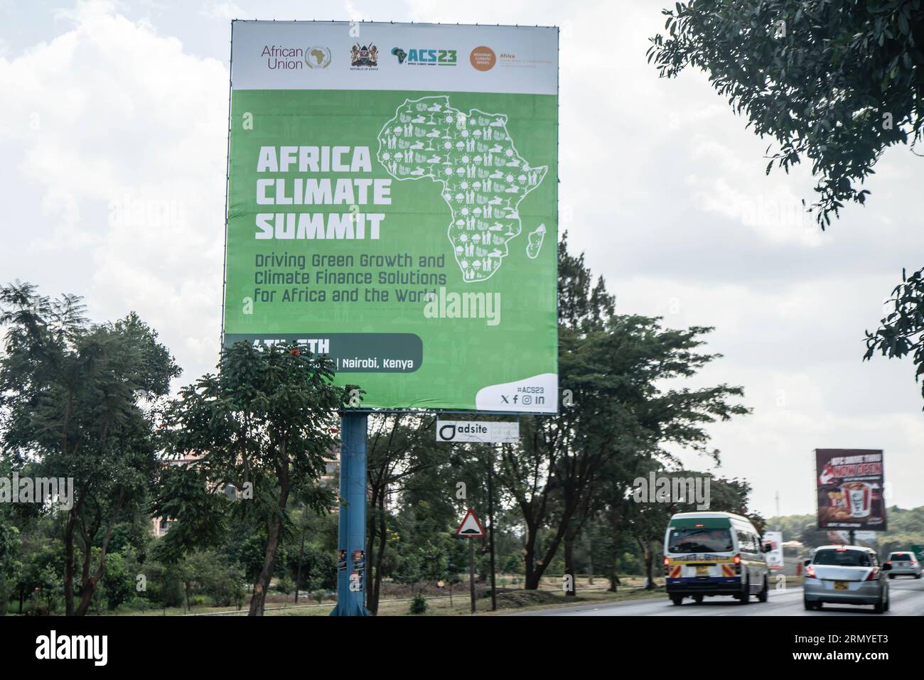 Vehicles drive past a poster detailing the upcoming Africa Climate ...