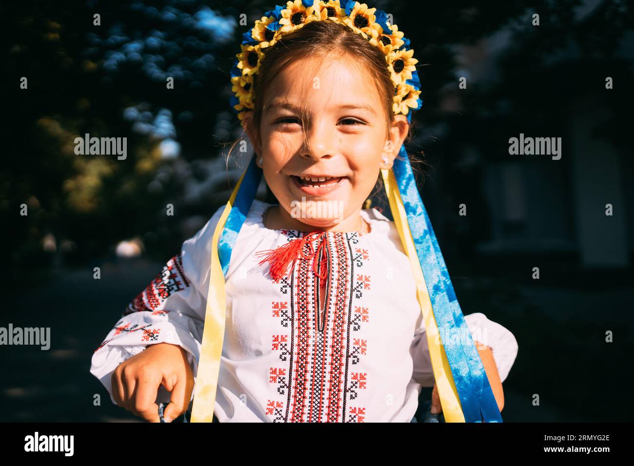 Child girl in Ukrainian traditional clothes and flower wreath is ...