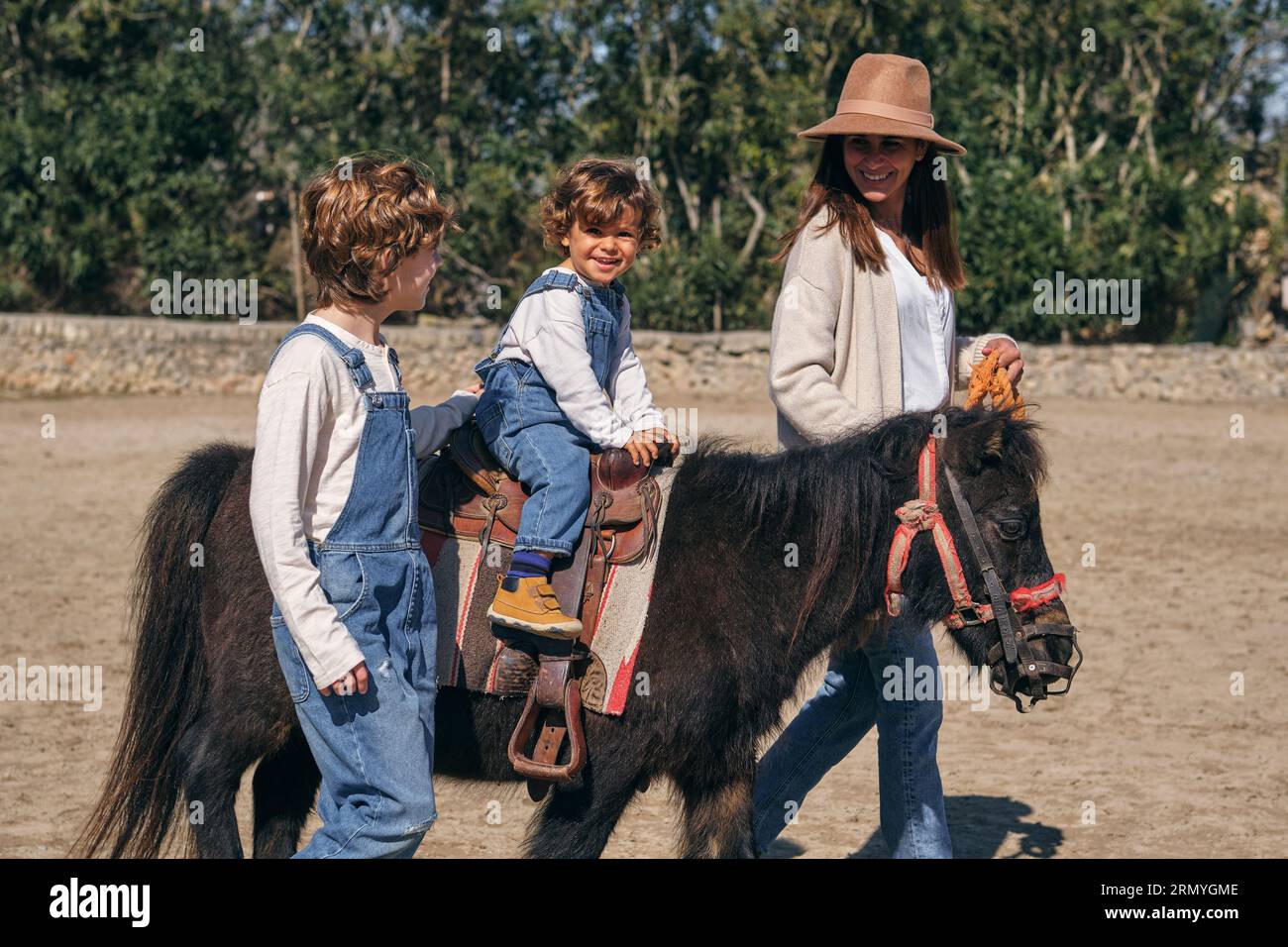 Side view of happy cute toddler in denim overall smiling and riding ...