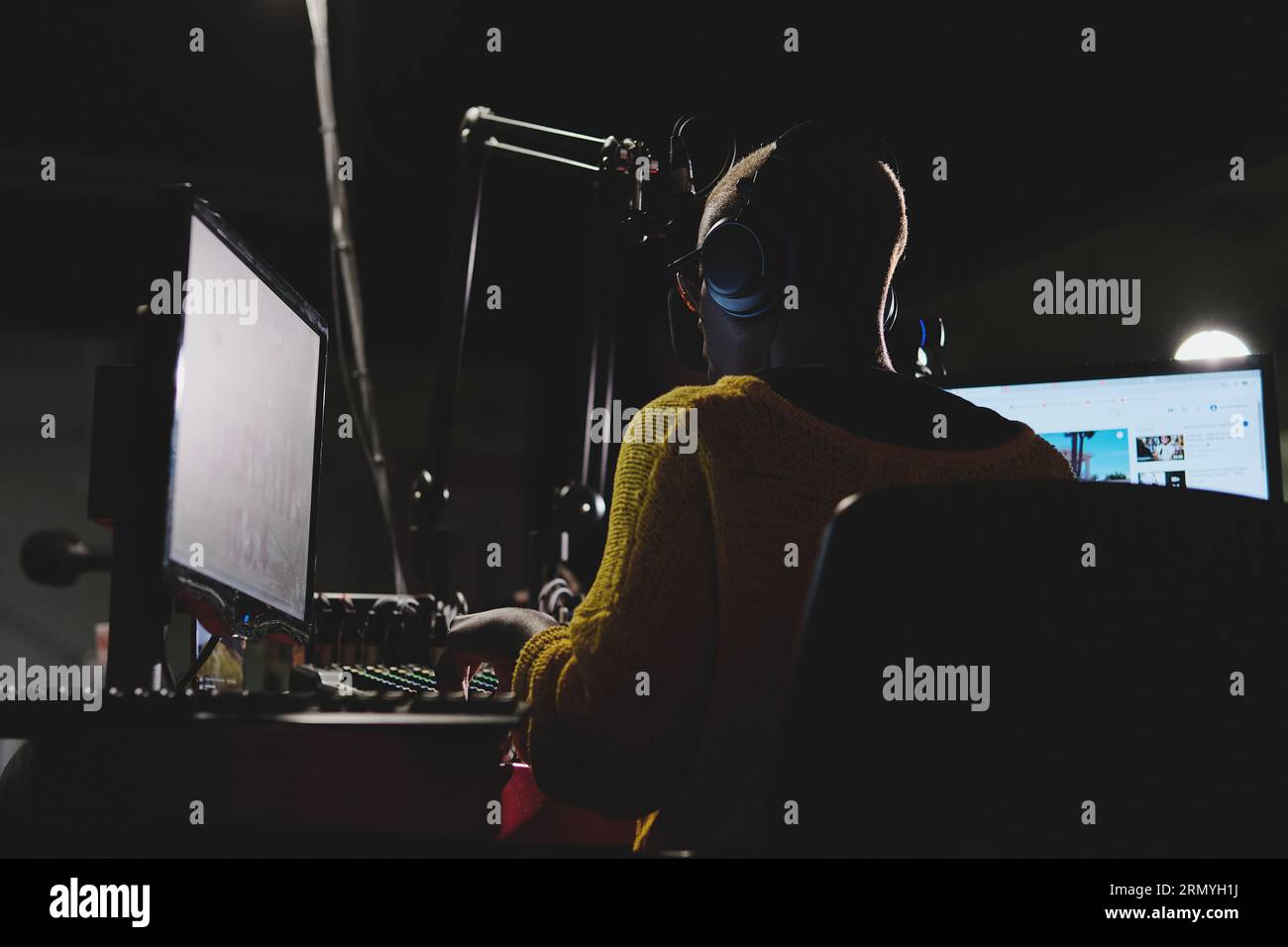 Back view of anonymous female radio host in headphones mixing audio ...