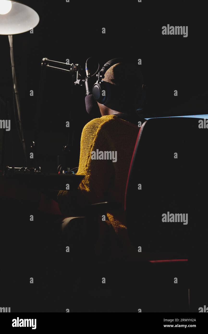 Back view of anonymous black female radio host in headphones speaking ...