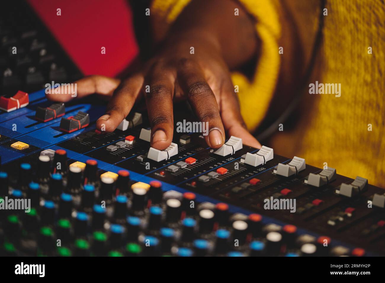 High angle of crop anonymous female sound engineer in yellow sweater ...