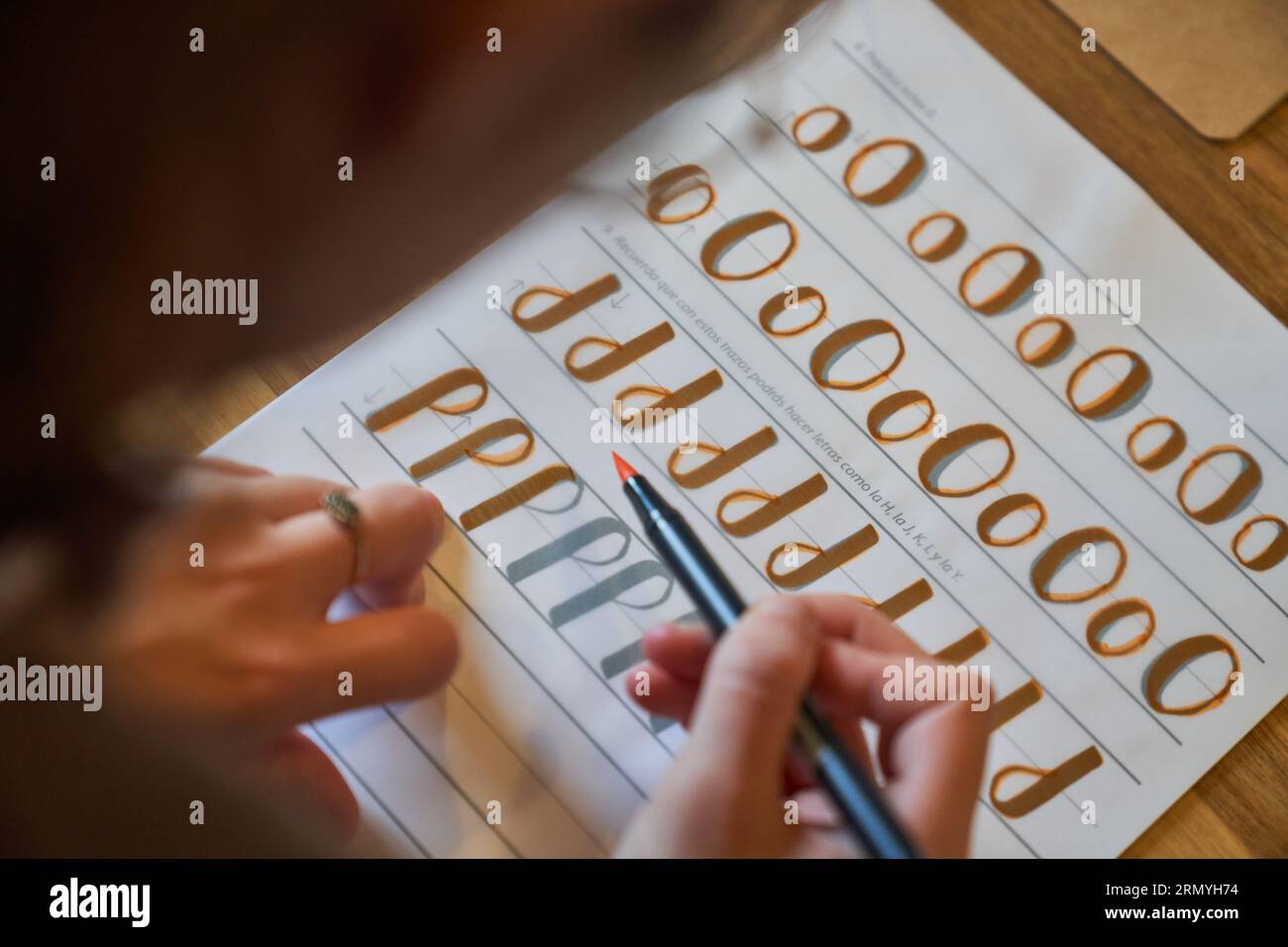 From above of crop unrecognizable artist drawing letters on lined paper ...