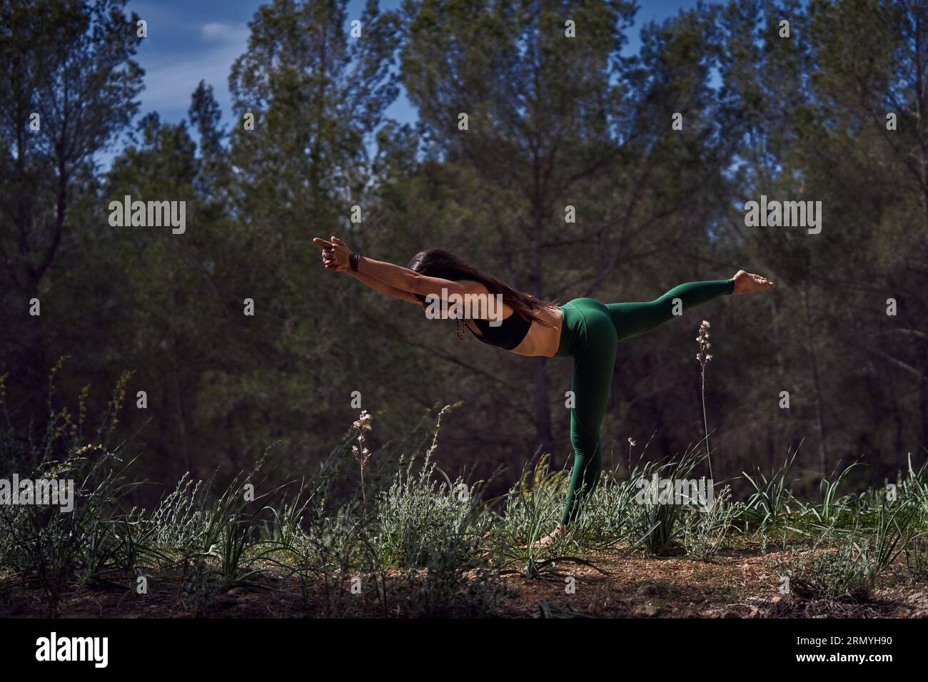 Full body side view of unrecognizable active barefoot female in activewear practicing ...