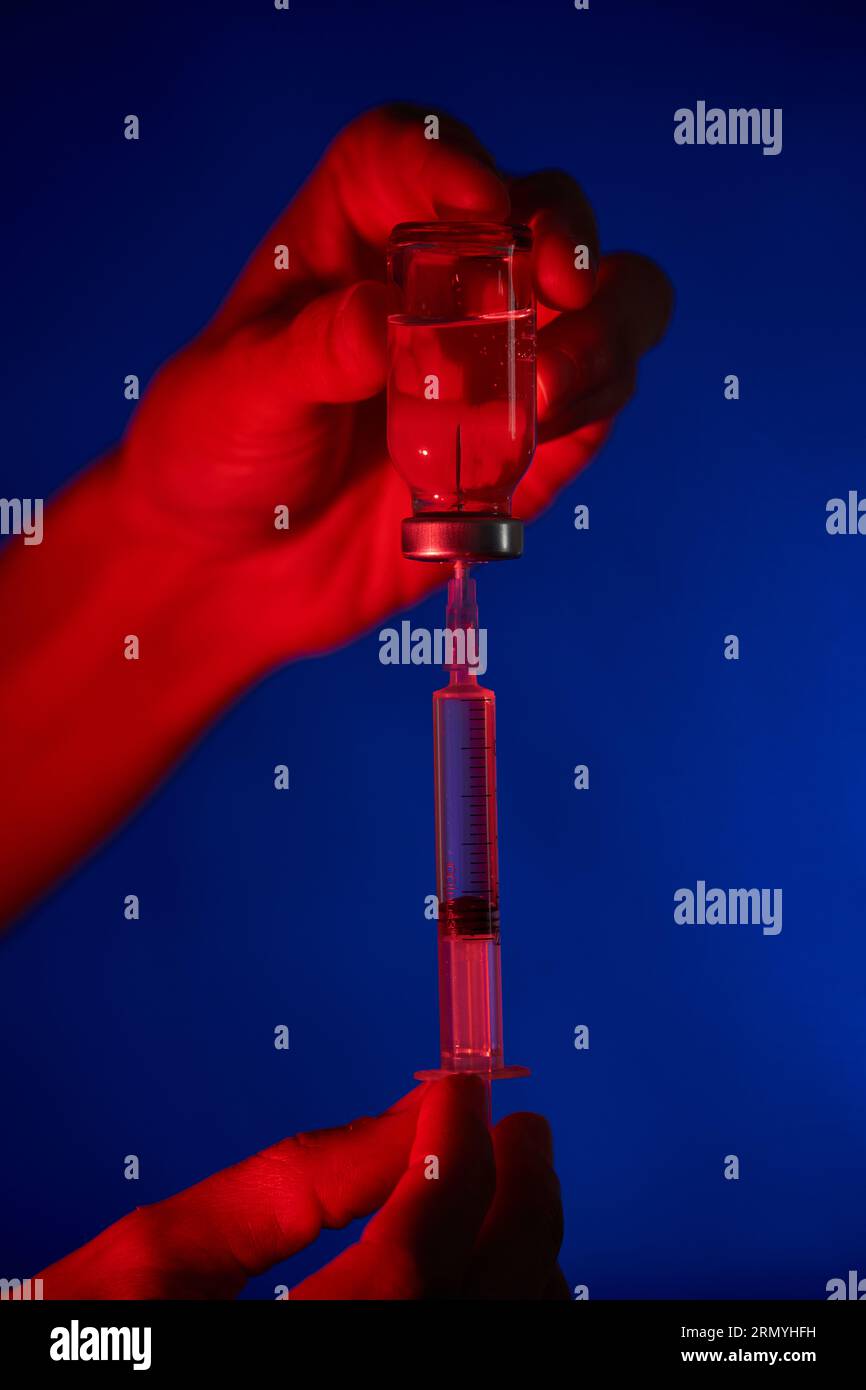 Unrecognizable person demonstrating syringe and vial filled with COVID ...