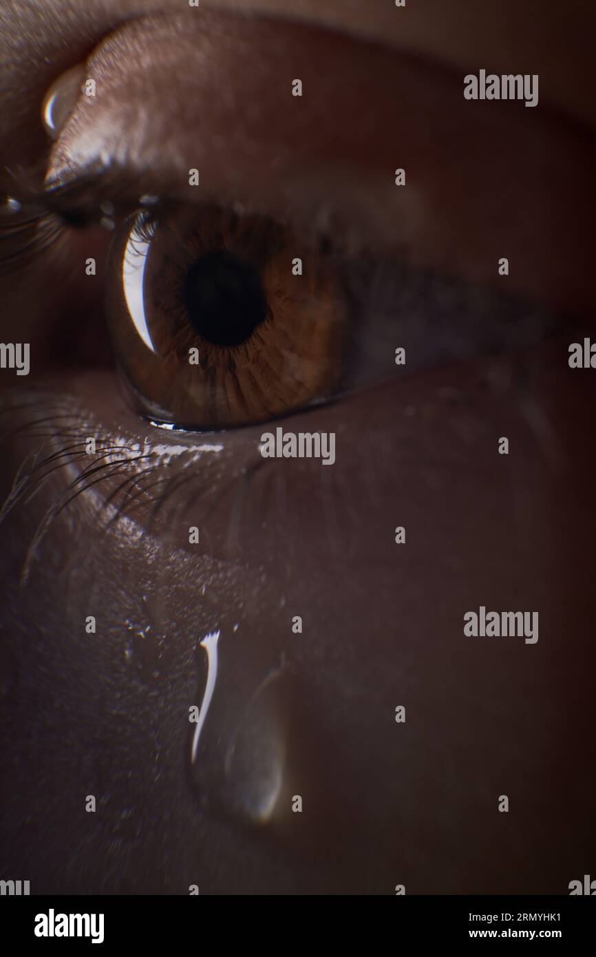 Closeup eye of crop anonymous sad kid with tears on eyelid and cheek ...
