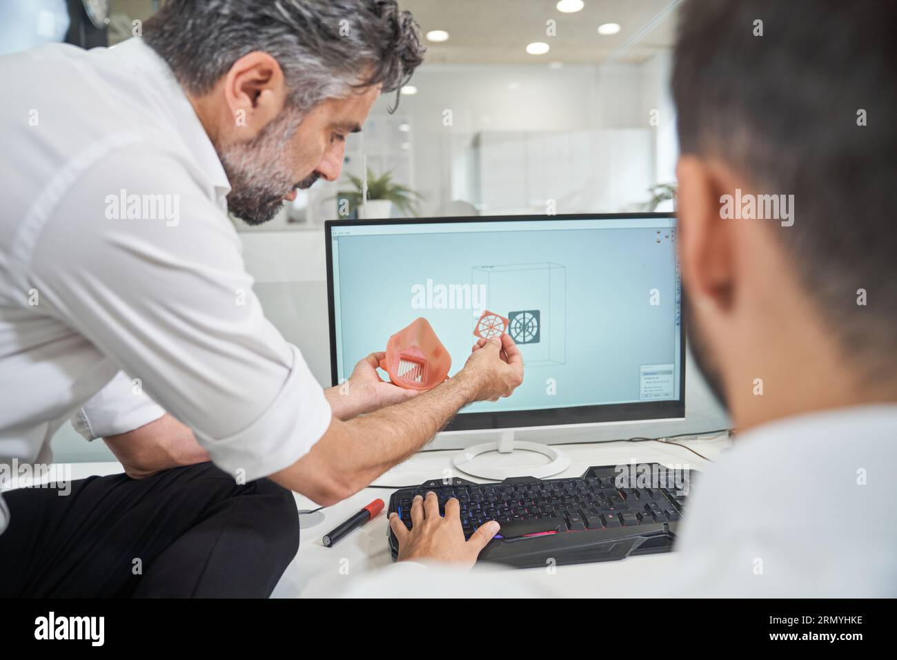 Bearded worker examining 3D printed model of respirator while working ...