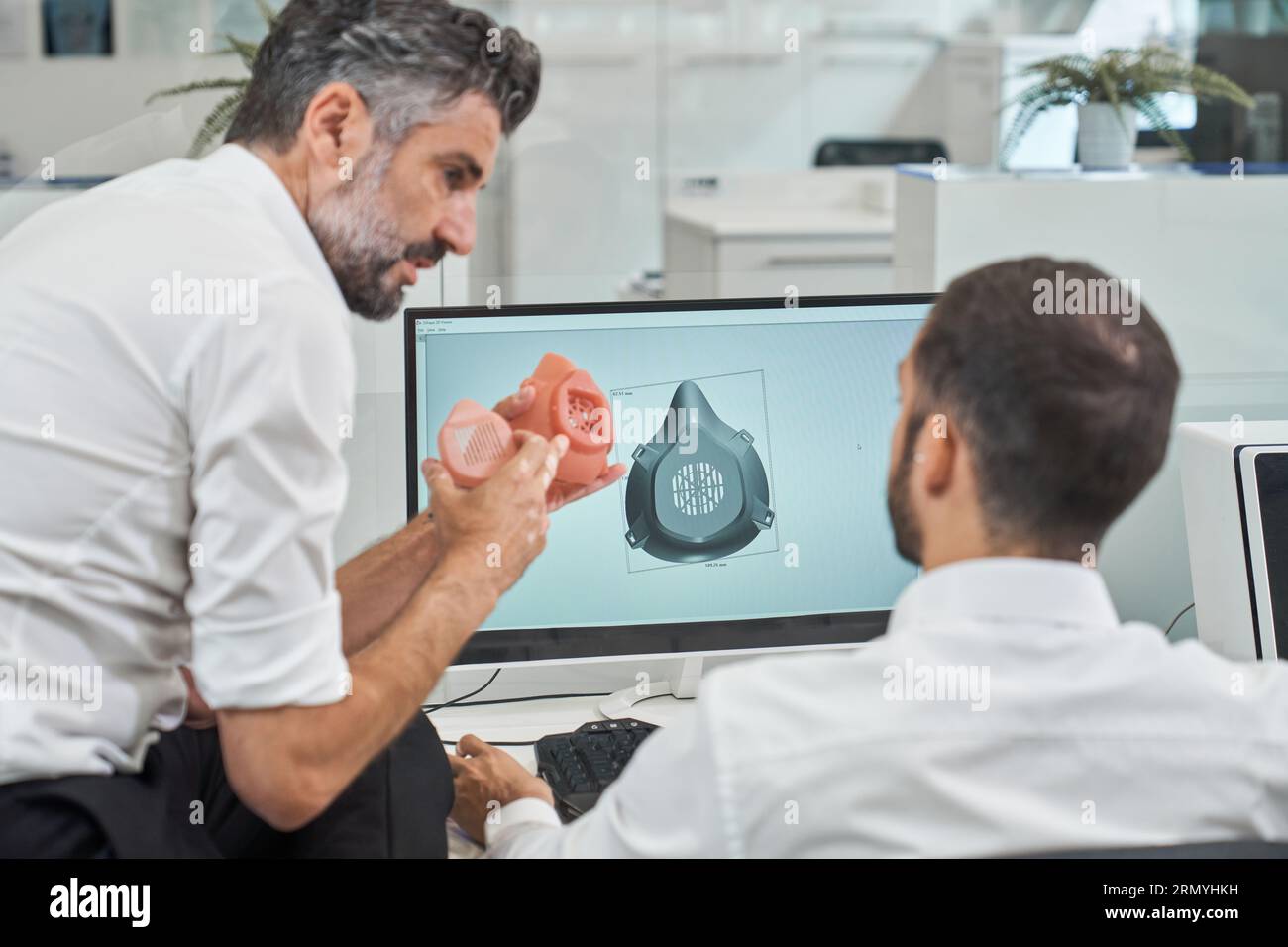 Competent male workers in formal clothes examining respirator while ...