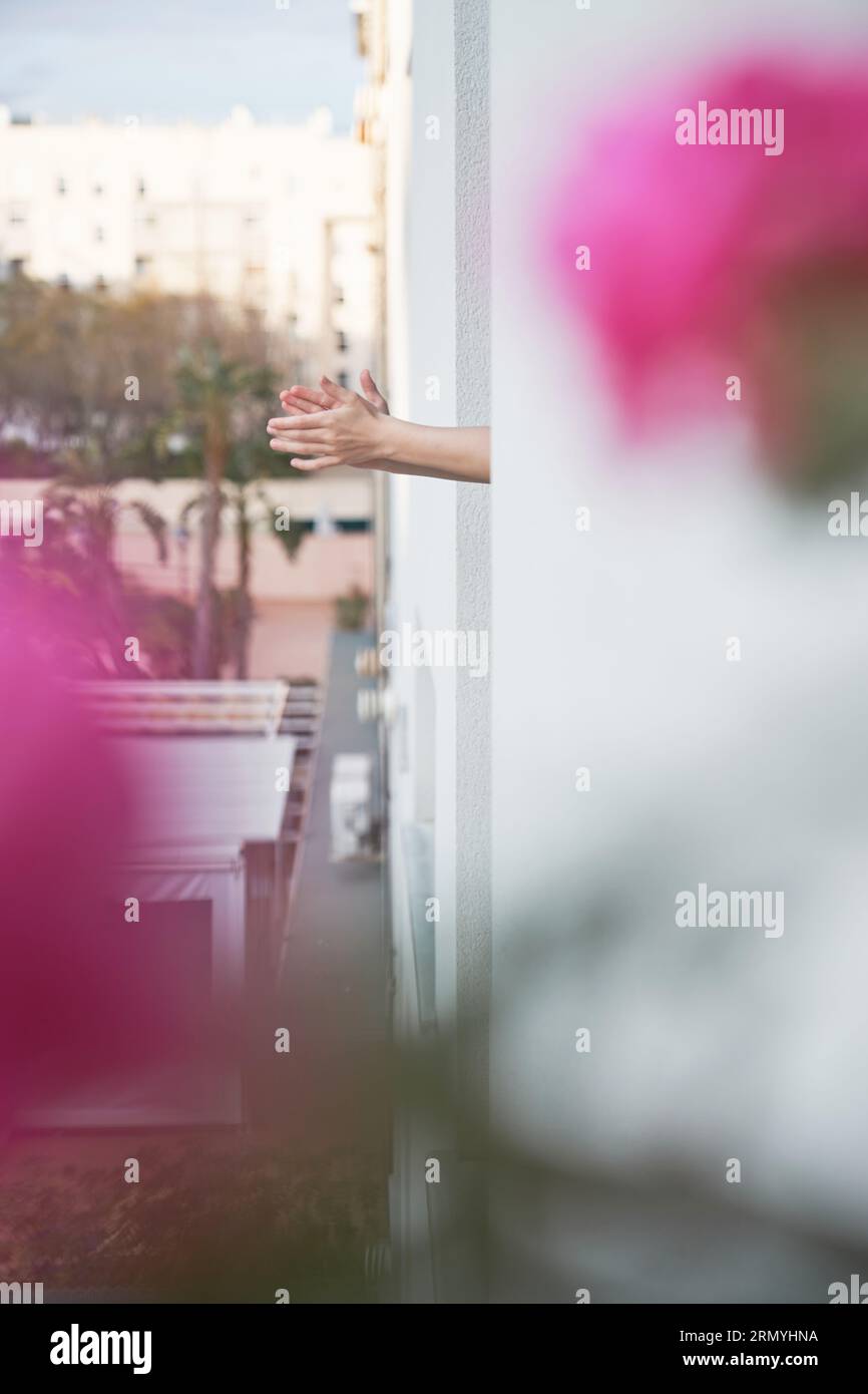 Anonymous person reaching hands out of window of multistory residential ...