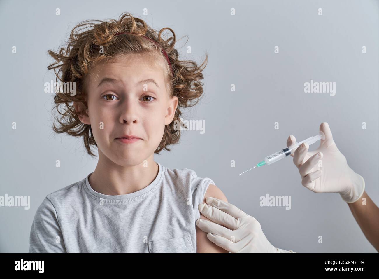Excited cheerful child smiling in camera while nurse bringing syringe ...