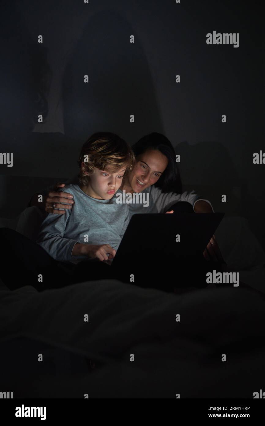 Positive mother helping kid in casual wear browsing internet on netbook ...