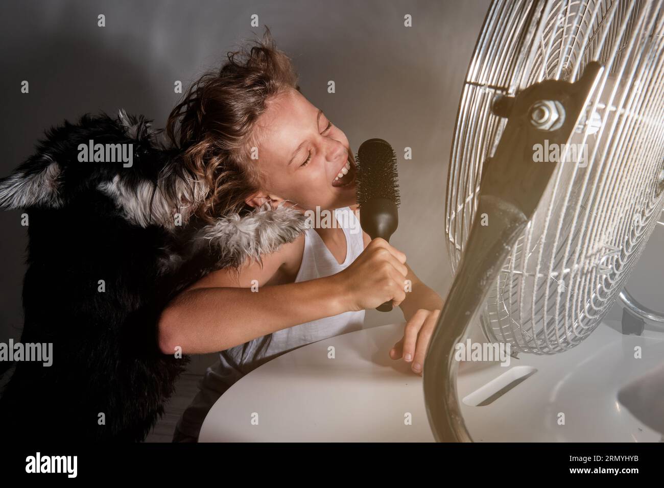 Funny boy with closed eyes playing with fluffy Miniature Schnauzer and ...
