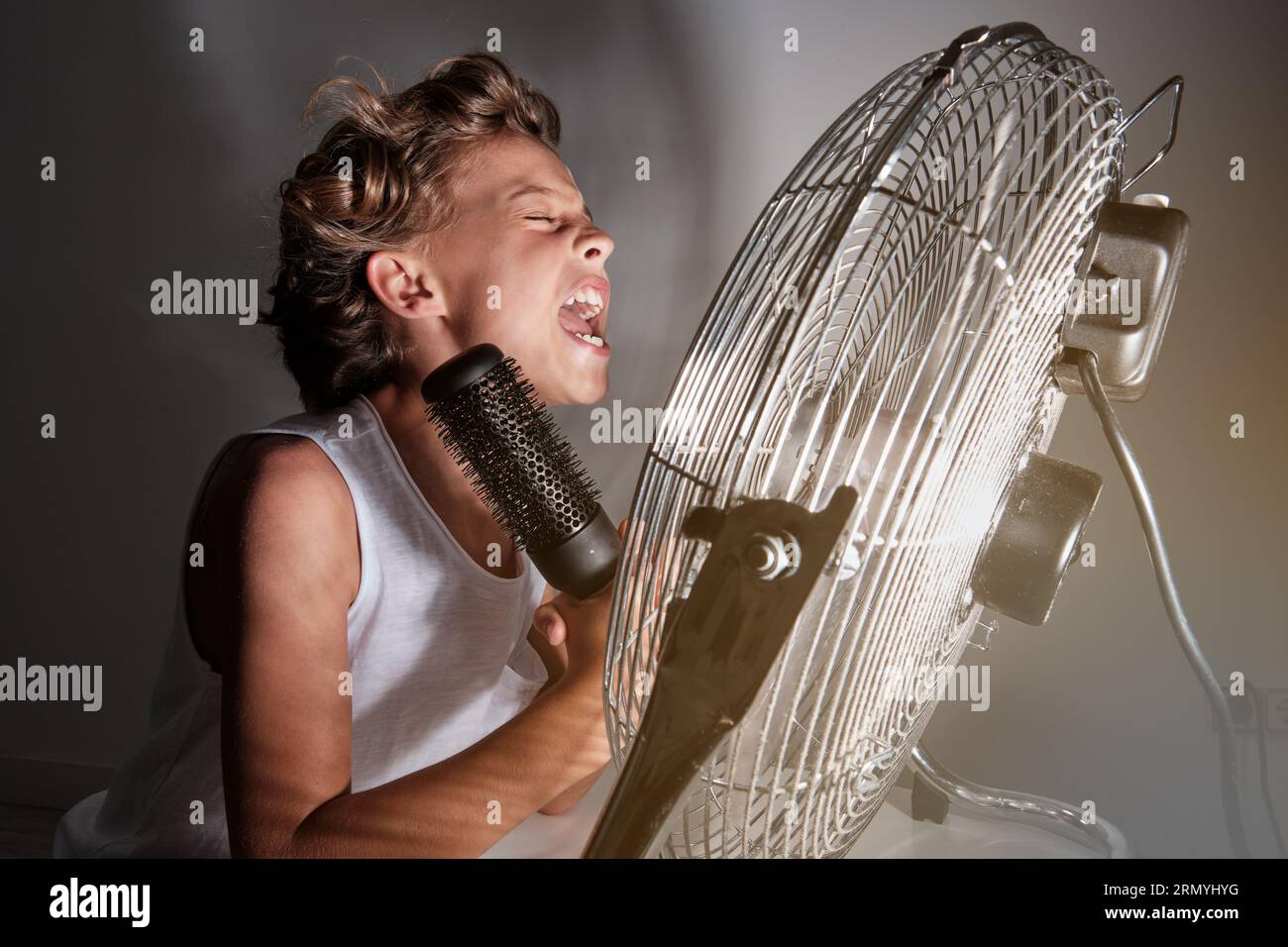 Side view of excited child enjoying cool air from fan and while ...