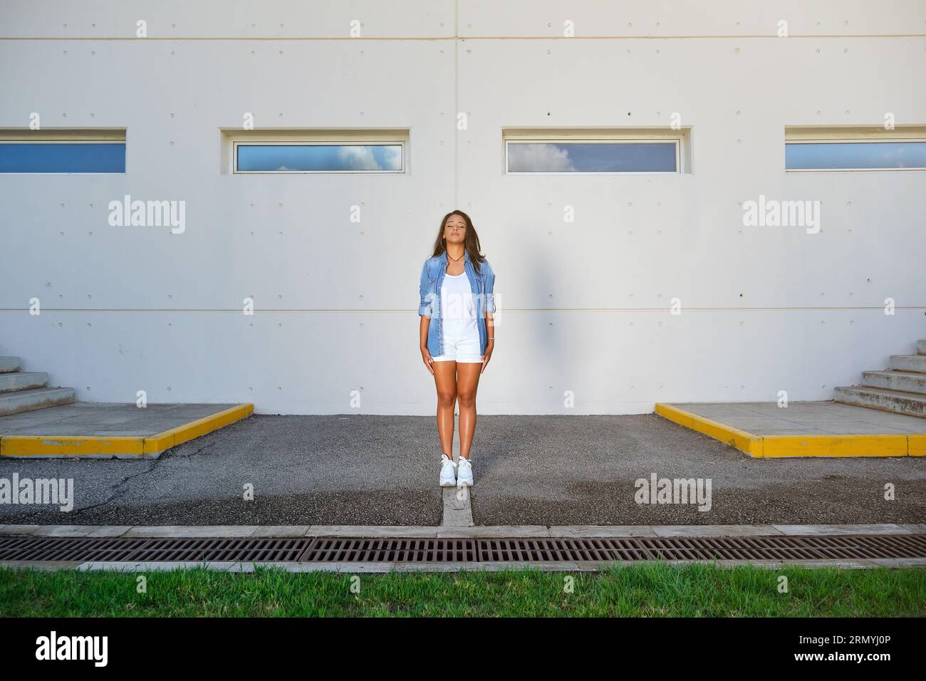 Full body of young female in casual outfit standing outside modern ...