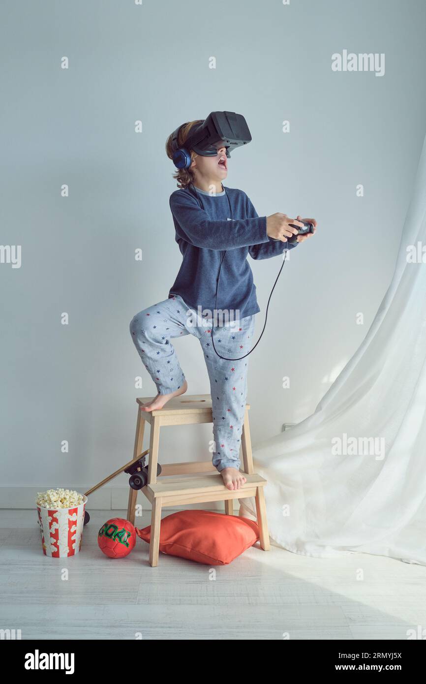 Full body of barefoot preteen boy in nightwear and VR headset and ...