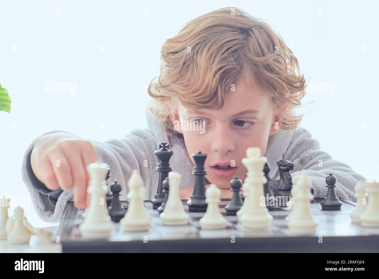 Concentrated preteen boy preparing performing check mate to rival while ...