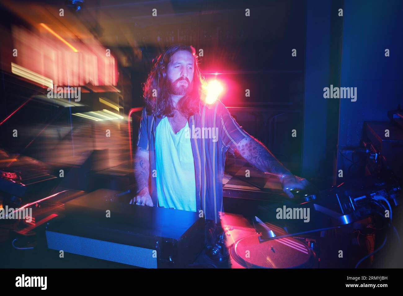 Talented male in casual wear standing at professional DJ setup while ...