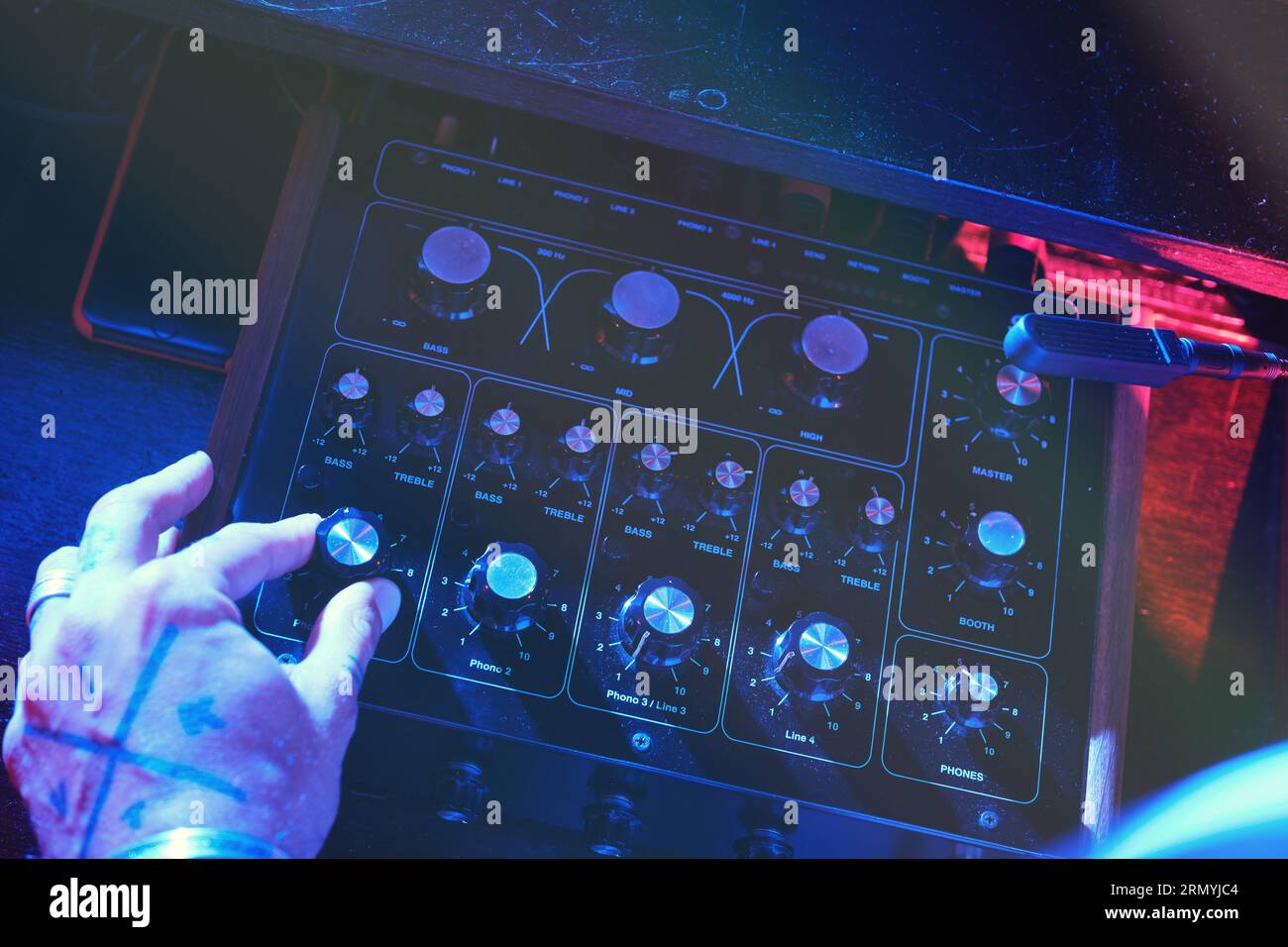 Hand of crop anonymous DJ turning knob on modern audio mixing console ...