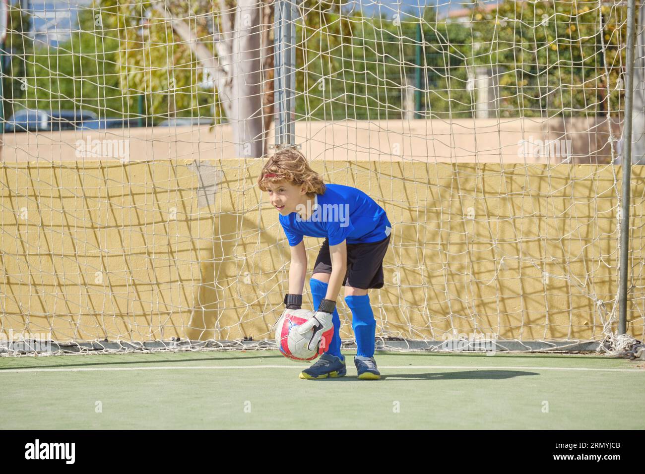 Full length of preteen goalkeeper in activewear leaning forward while ...