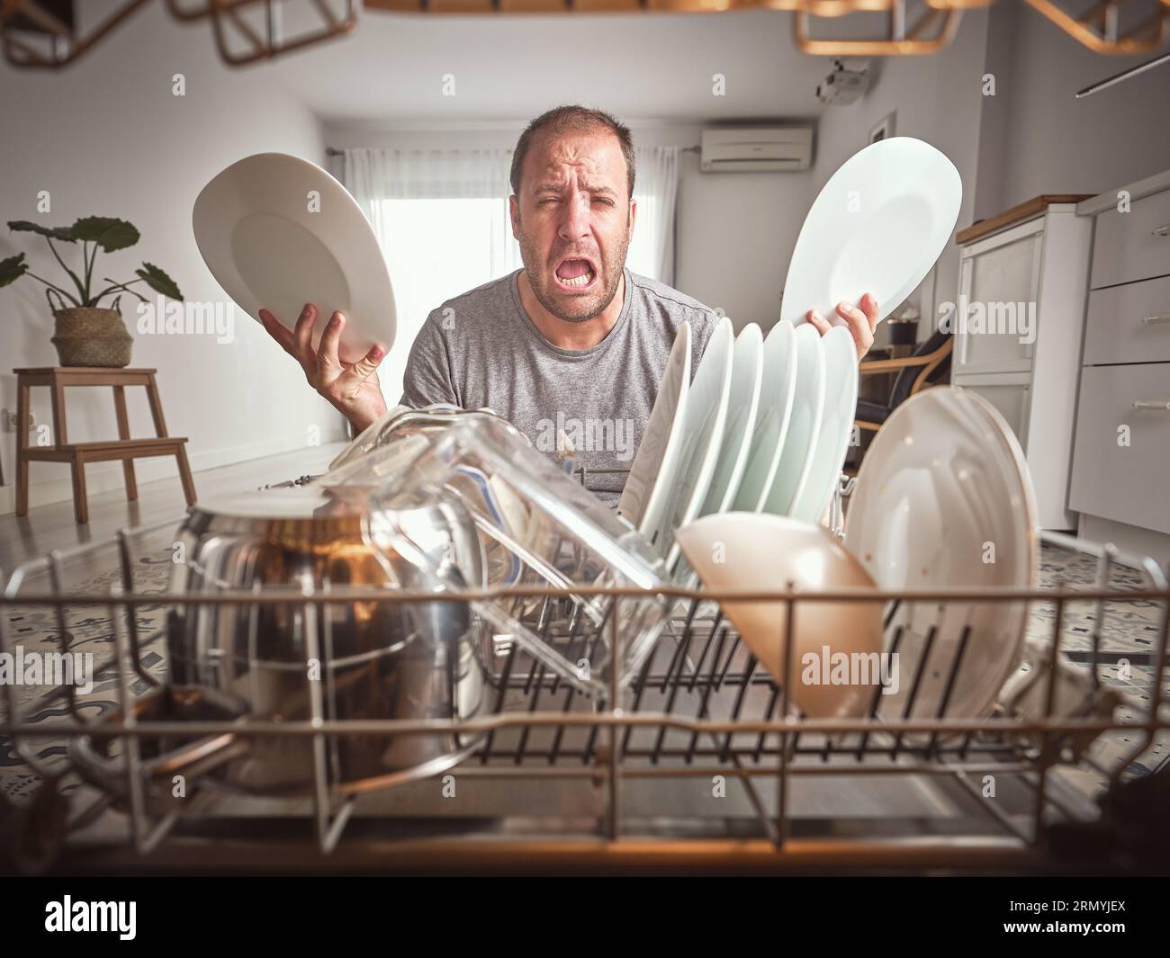 Unhappy male with clean plates in hands crying while standing near ...