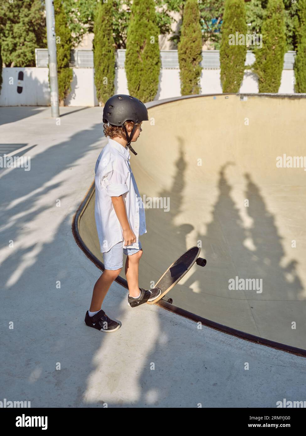 Side view full length of young skater standing with longboard on ramp ...