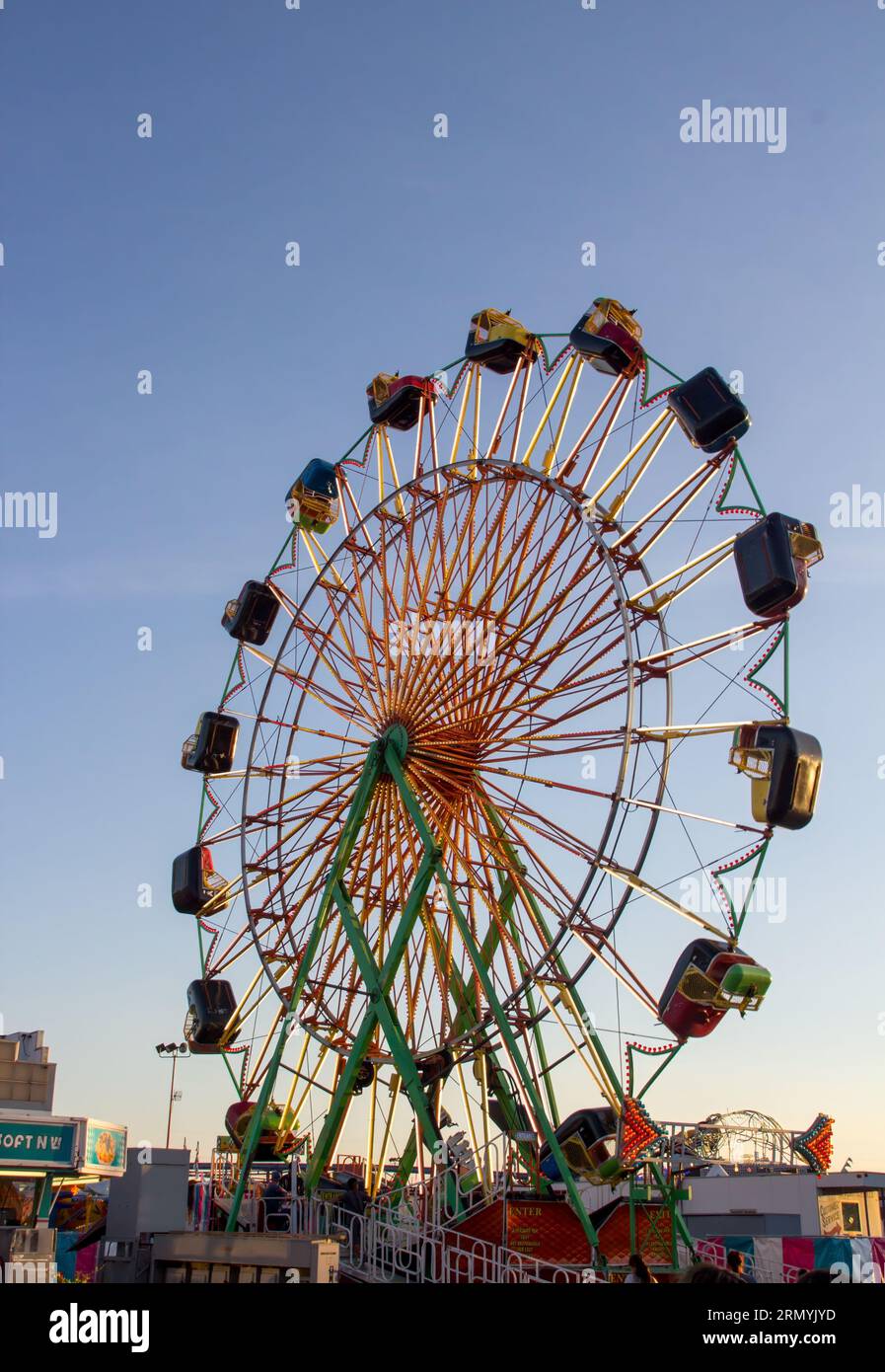 A brightly lit large Farris wheel with caged cars is against a bright ...