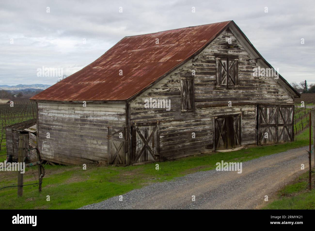 An old weather worn wooden barn with a red metal roof stands beside a ...
