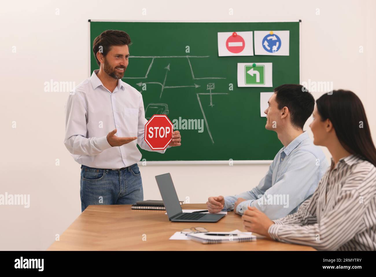Teacher showing Stop road sign to audience during lesson in driving ...