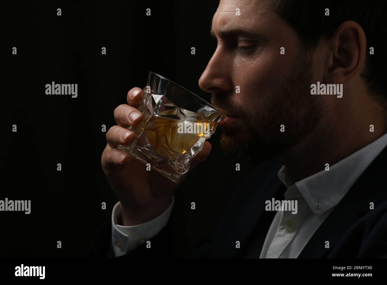 Man in suit drinking whiskey on black background Stock Photo - Alamy