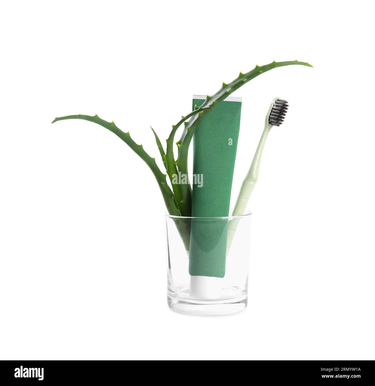 Tube of toothpaste, brush and aloe vera leaves in glass on white ...